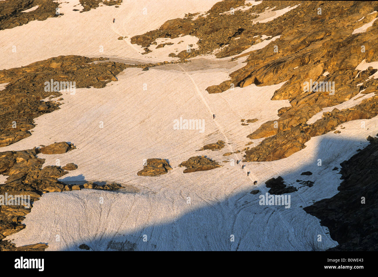String of mountain climbers on a snowy trail in morning light, Alps ...