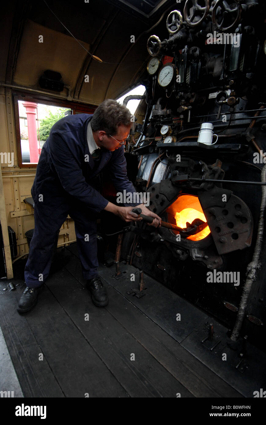 A fireman on the footplate shoveling coal on the steam locomotive of ...