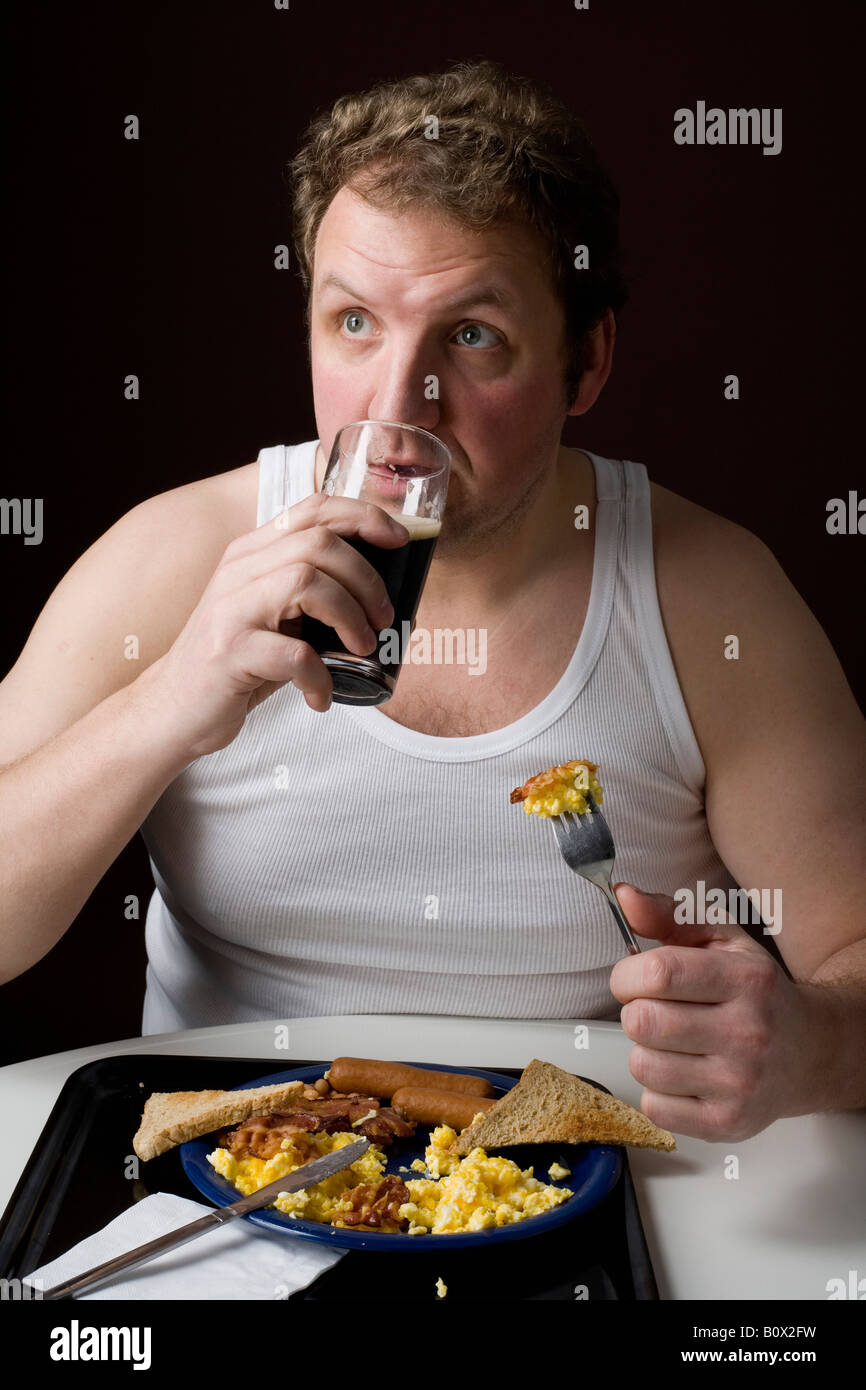 Stereotypical Englishman eating English breakfast and drinking a pint ...