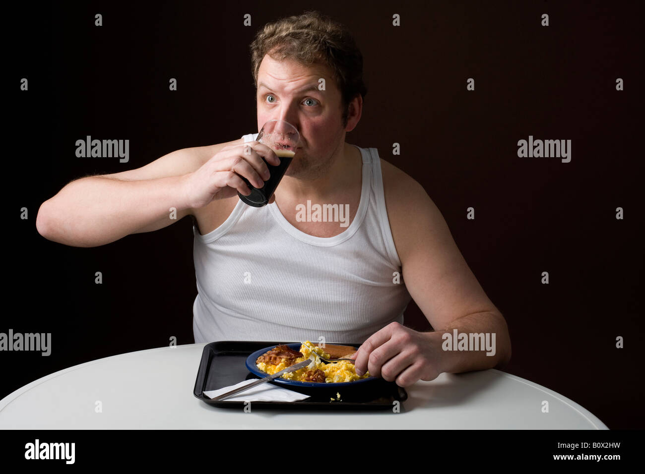 Stereotypical Englishman eating English breakfast and drinking a pint ...