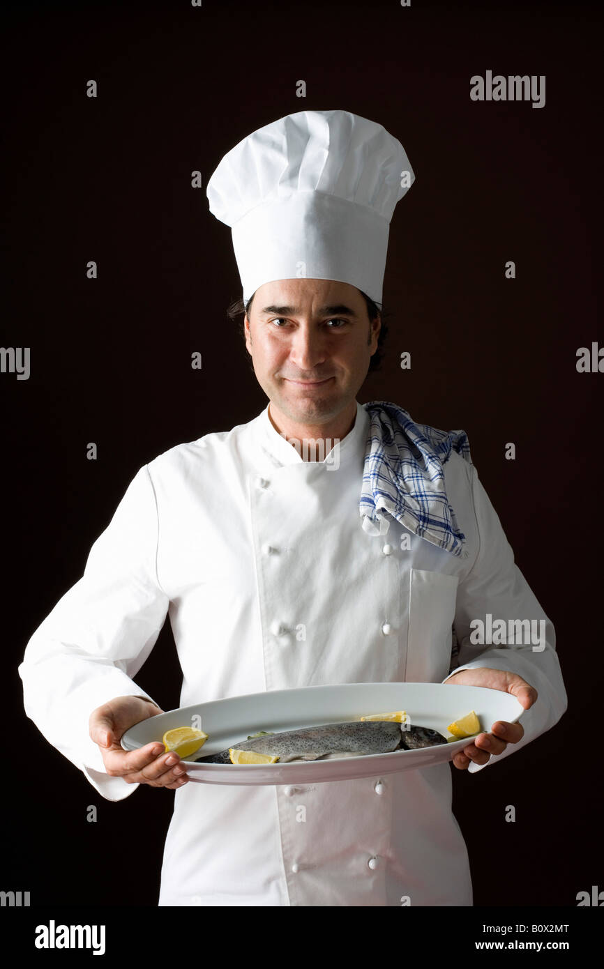 Stereotypical chef posing with a platter of fish Stock Photo - Alamy