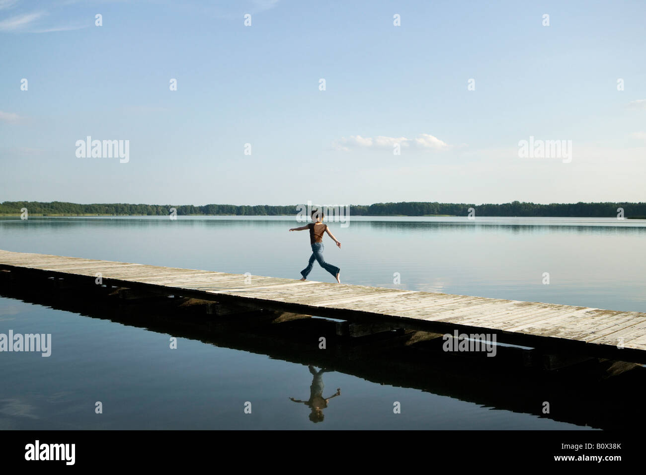 A woman running along a jetty Stock Photo - Alamy