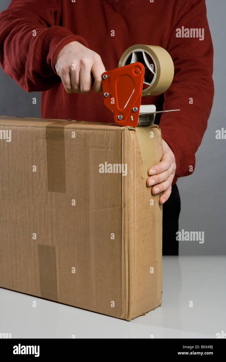 A man taping a cardboard box Stock Photo - Alamy