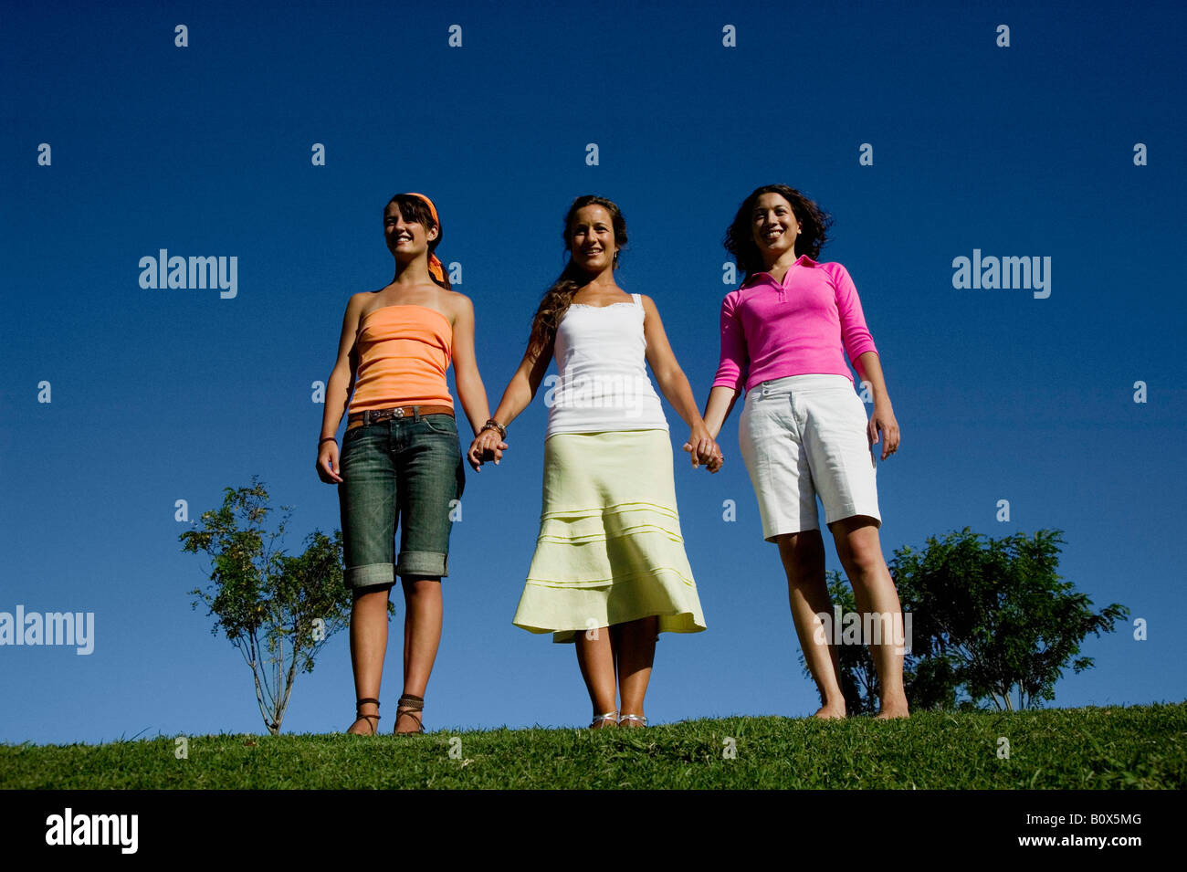 Three friends standing in a row and holding hands Stock Photo - Alamy