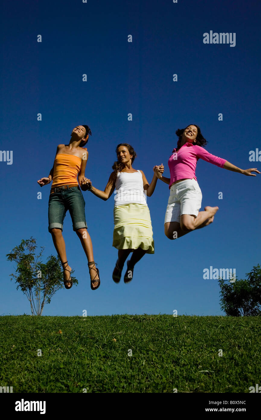 Three friends jumping in mid air Stock Photo - Alamy