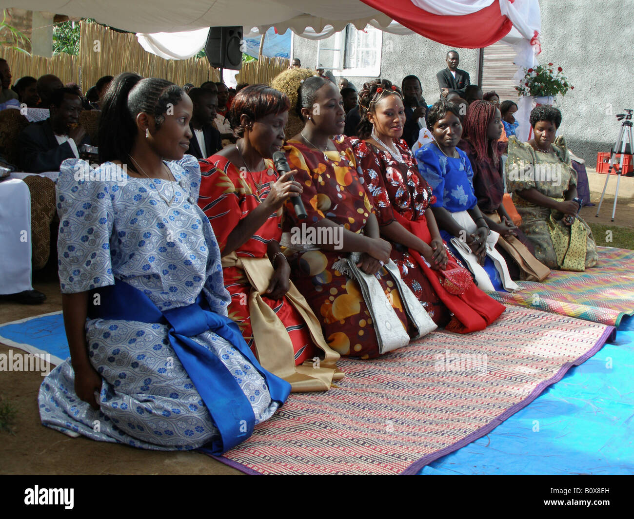 Kneeling young Ugandan ladies performing rituals at an engagement ...