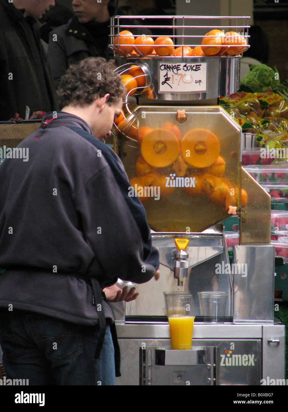 man squeezes fresh orange juice with a press on the Borough Market ...