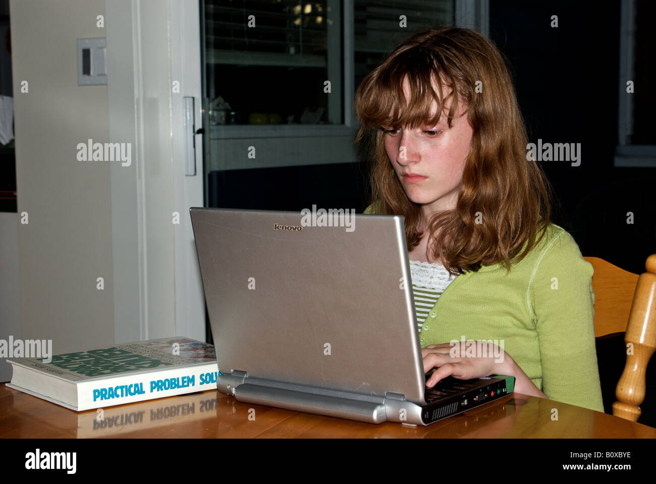 Teenage high school student solving homework problems on her laptop ...