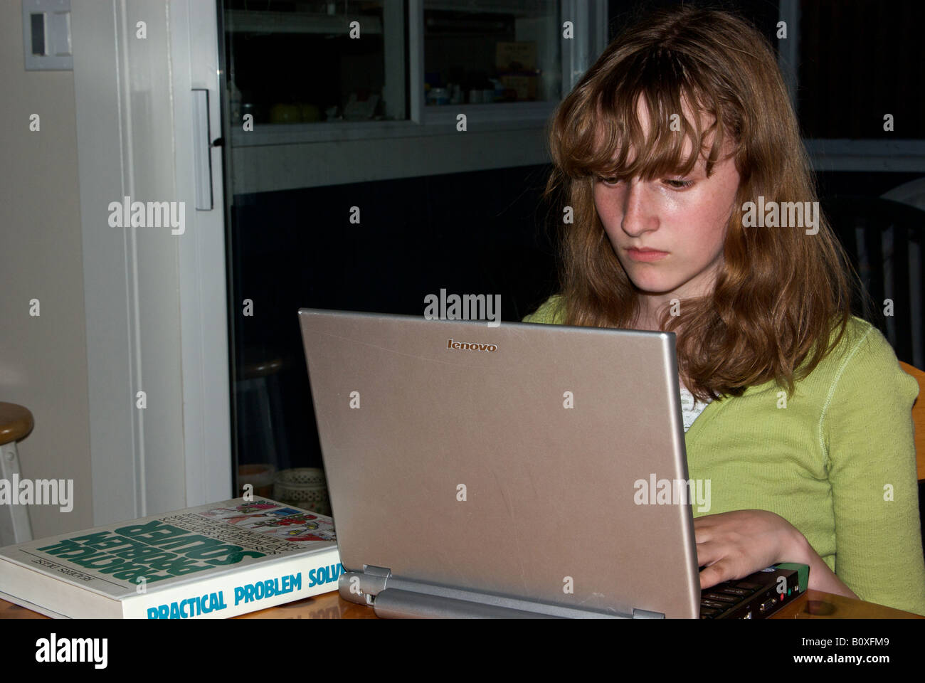 Teenage high school student solving homework problems on her laptop ...