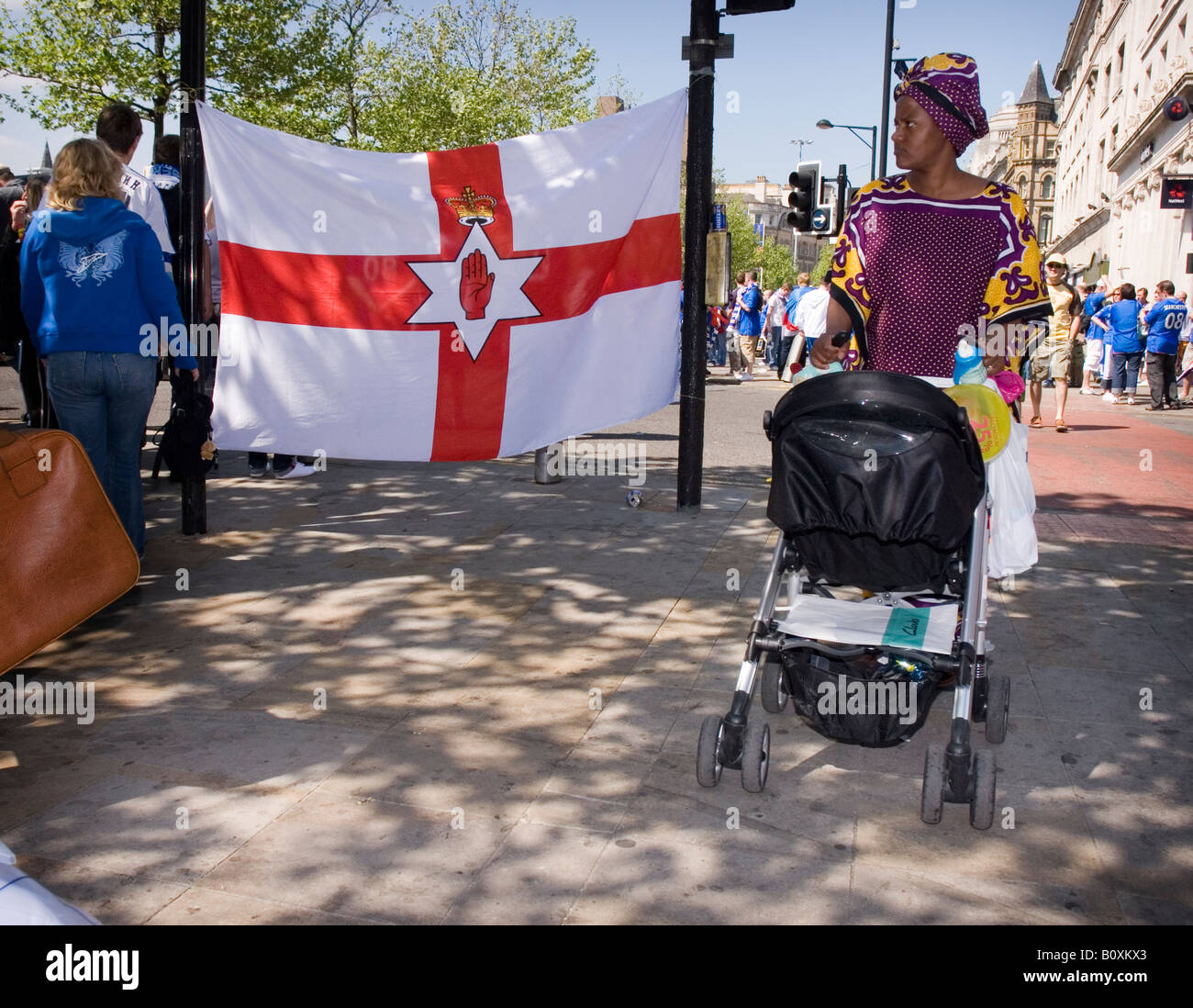 A black woman walks past a red hand Ulster flag erected by Glasgow ...