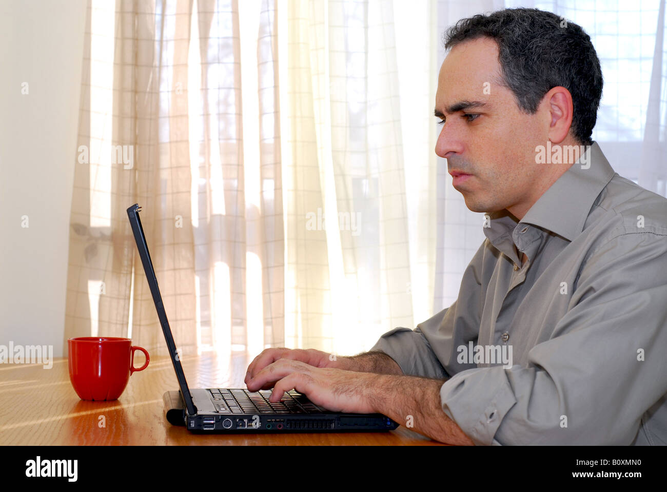 Man sitting at a desk and working on his computer Stock Photo - Alamy