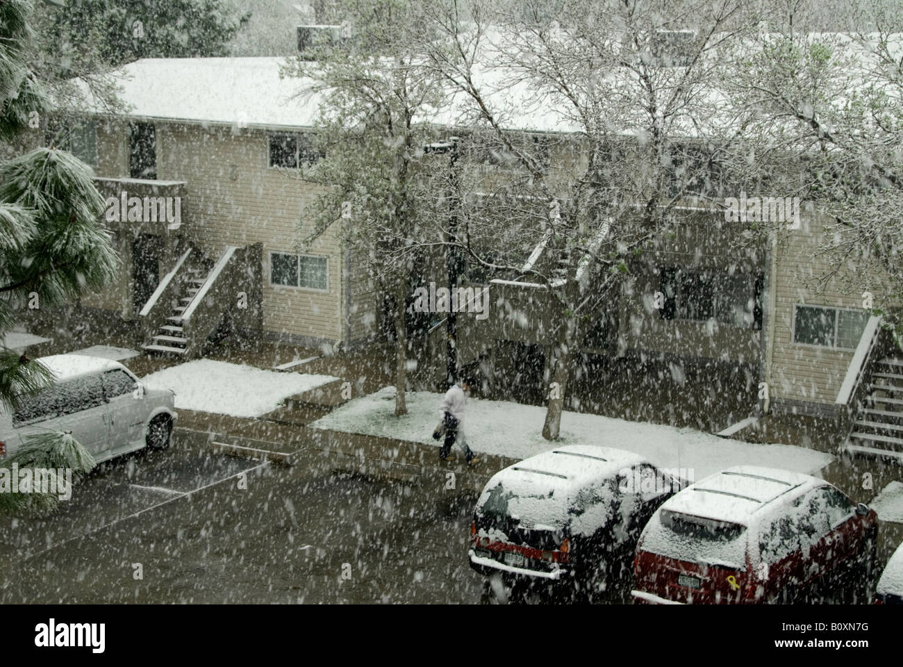 Person walks along apartment building as snow is falling during spring ... Person walks along apartment building as snow is falling during spring ...