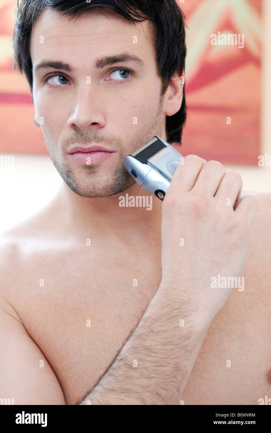 Young man using electric razor, portrait Stock Photo - Alamy