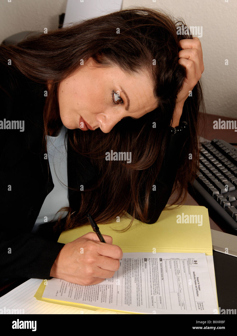 female executive in the office, signing her tax forms while sitting at ...