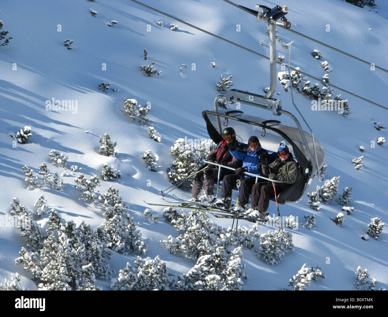 Skiers sitting in a chair ski lift in snowy mountain scenery of a ...