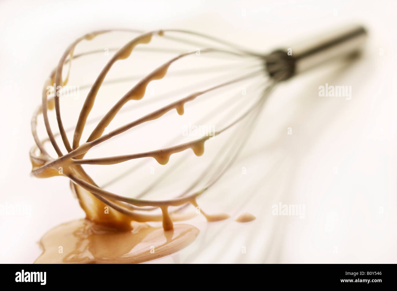 Metal whisk with creamy mixture dripping of it Stock Photo - Alamy