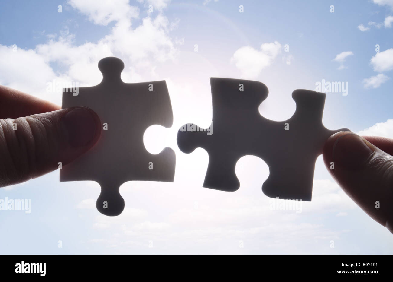 Hands trying to fit two puzzle pieces together Stock Photo - Alamy