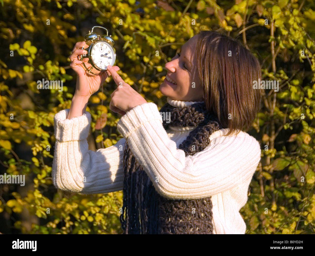 woman in autumn, pointing on a clock in her hand Stock Photo - Alamy