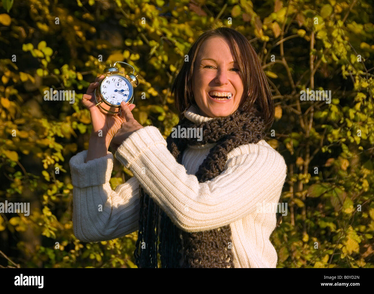 woman in autumn, pointing on a clock in her hand Stock Photo - Alamy