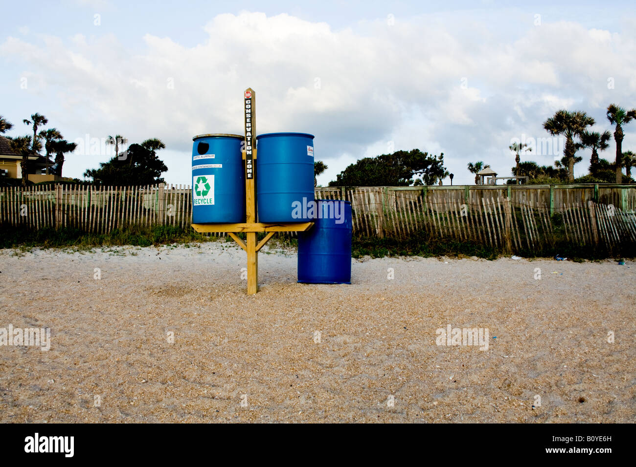 Two recycling elevated blue trash barrels next to a receptacle on the ...