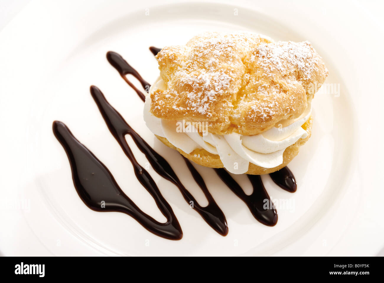 Cream puff with chocolate sauce on plate Stock Photo - Alamy