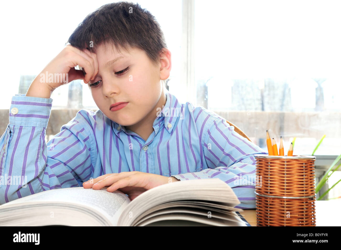Serious school boy studying with a book Stock Photo - Alamy