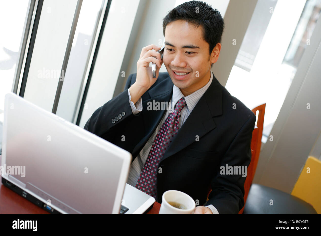 Young man in a cafe with laptop, talking on a mobile phone, Washington ...