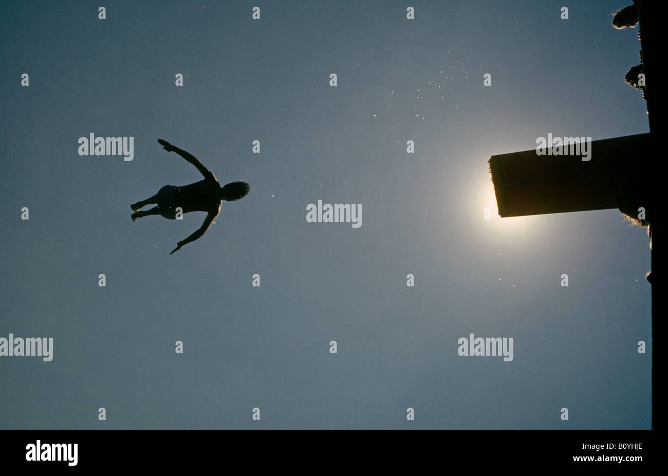A boy dives off a homemade diving board attached to the top deck of a ...