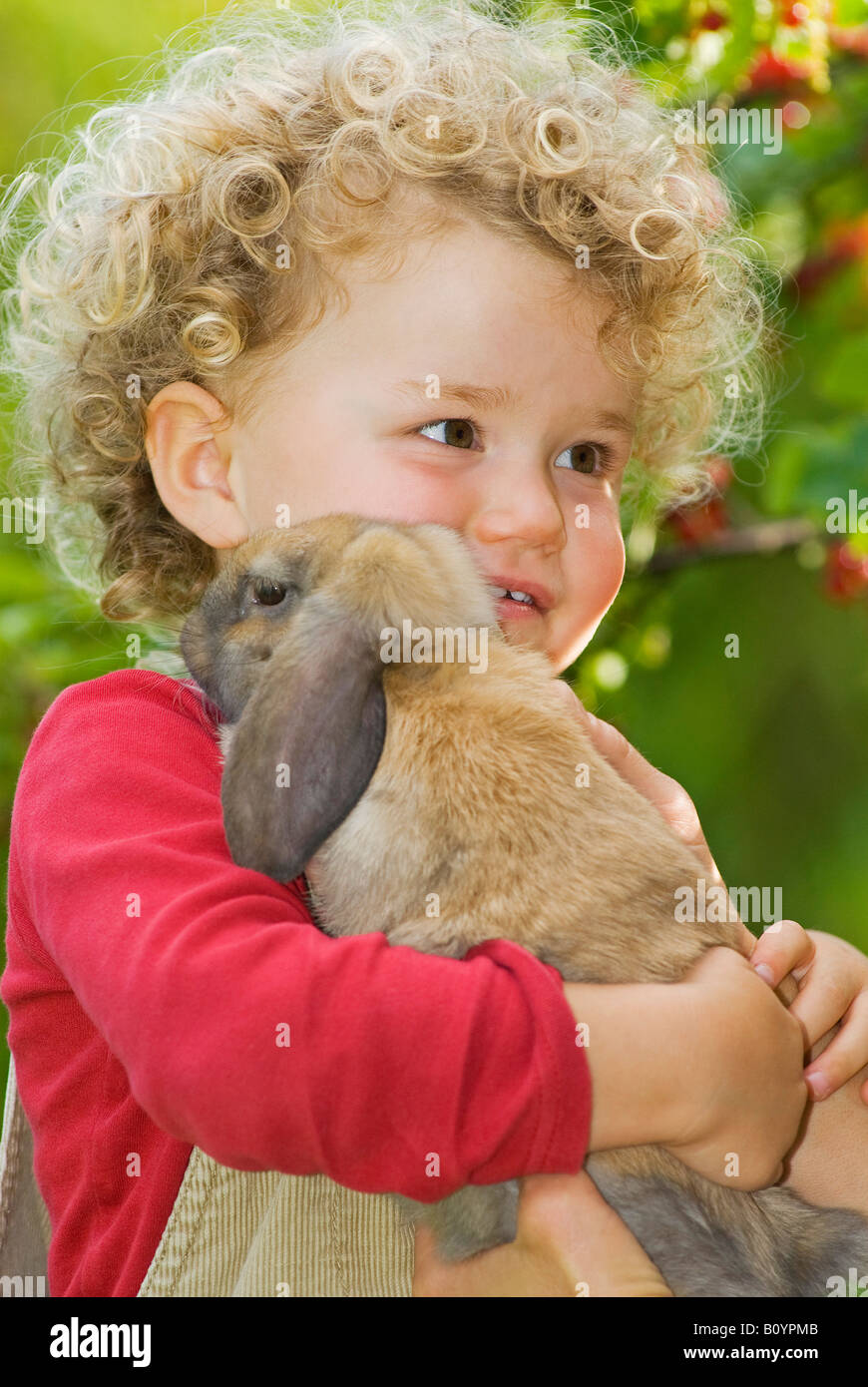 Blonde girl (4-5) with curly hair holding rabbit, portrait Stock Photo ...