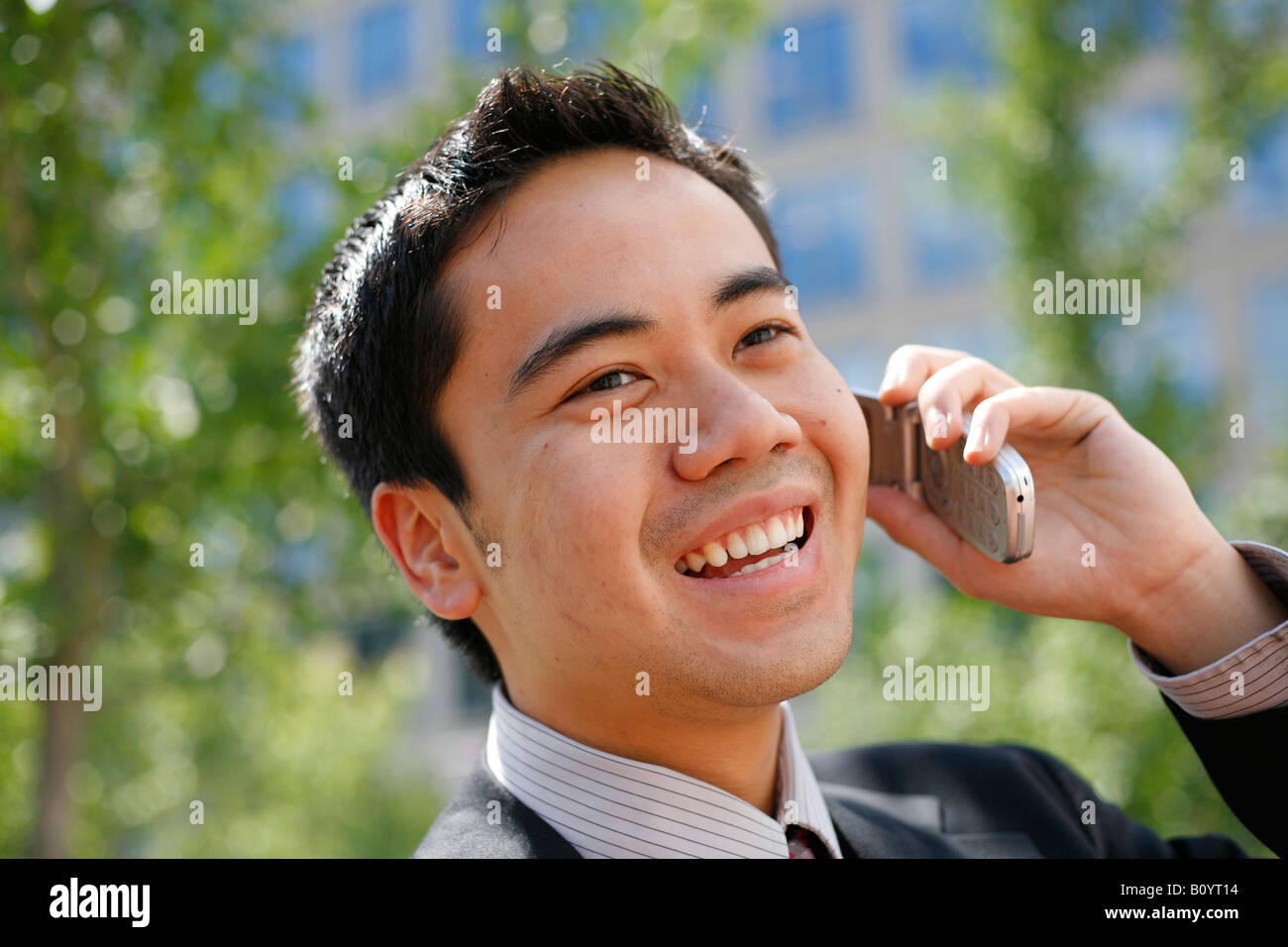 Young businessman standing in front of office building talking on ...