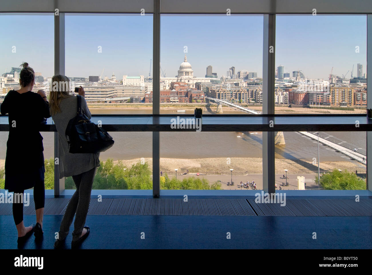 Horizontal wide angle of girls enjoying the view through a large window ...