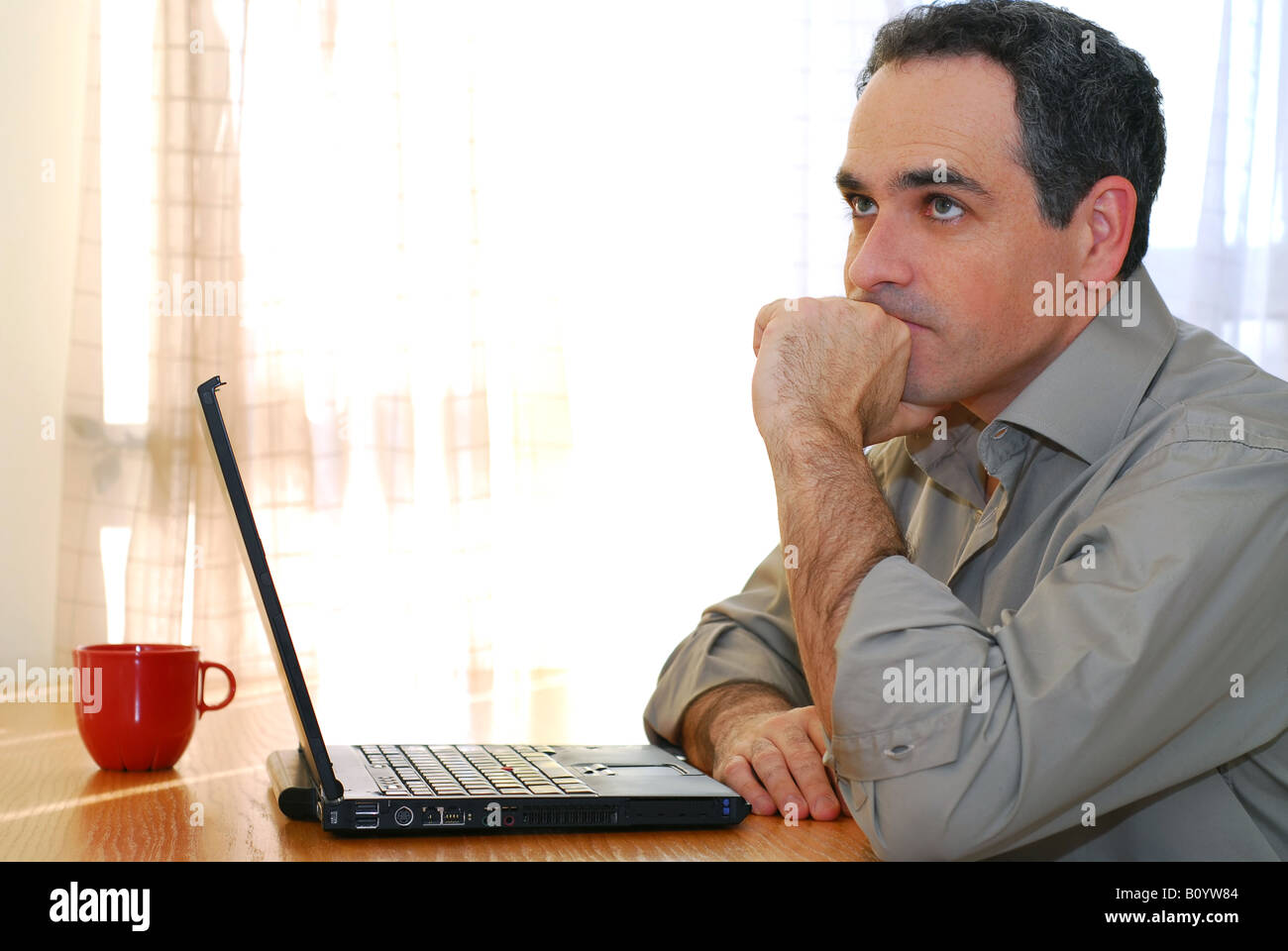 Man sitting at a desk and looking into his computer Stock Photo - Alamy