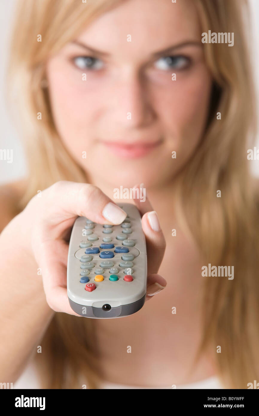 Blonde woman using remote control, portrait Stock Photo - Alamy