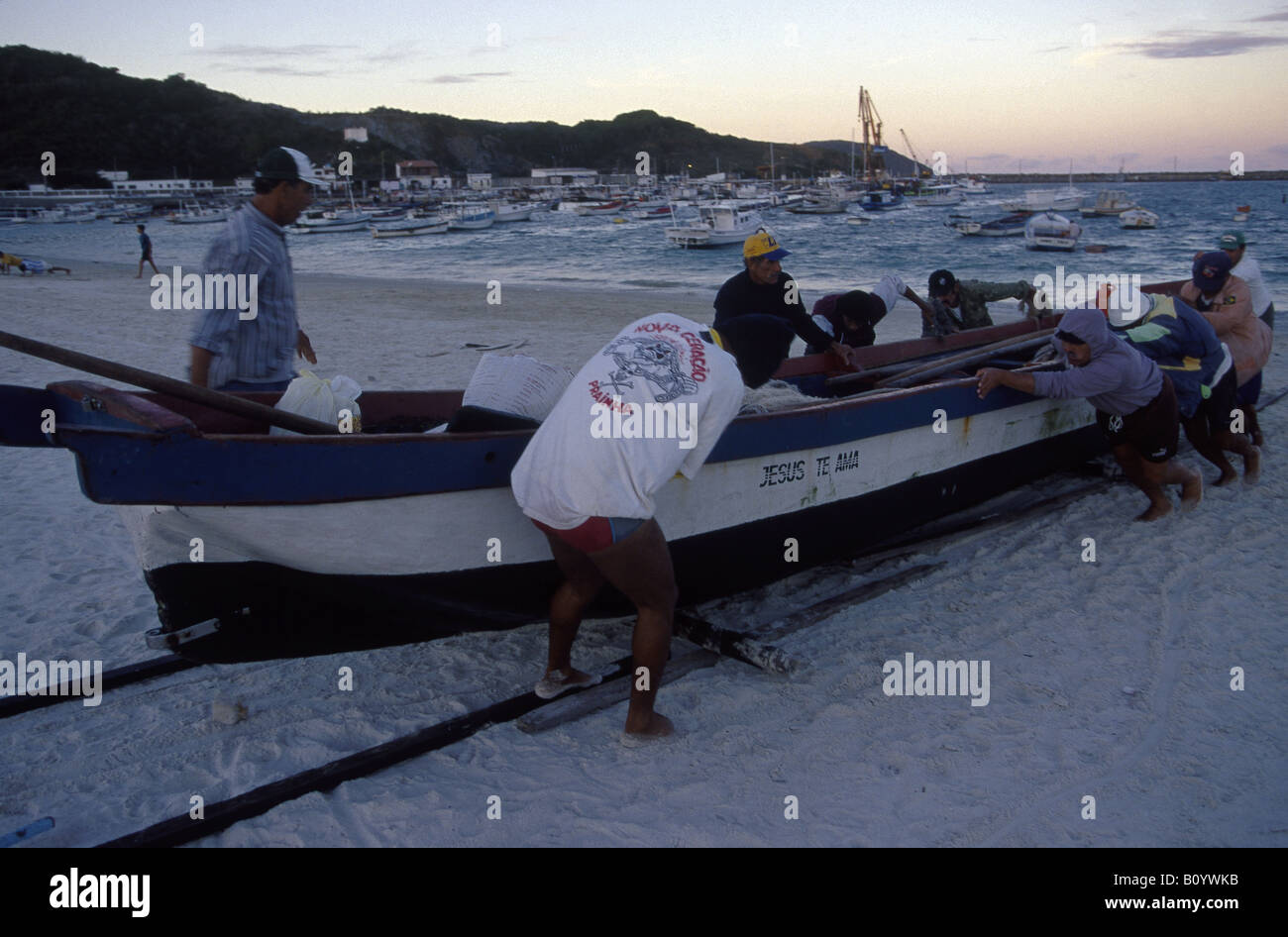 Sea inlet harbour Fishing boats Men beaching long narrow boat Sunset ...