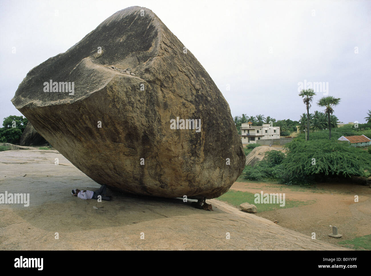 Man lying under huge lump of rock at Mamallapuram Mahabalipuram MADRAS ...