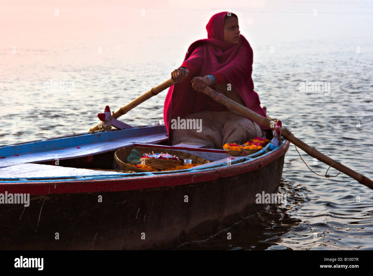 INDIA VARANASI Indian woman rowing a boat on the Ganges River at ...