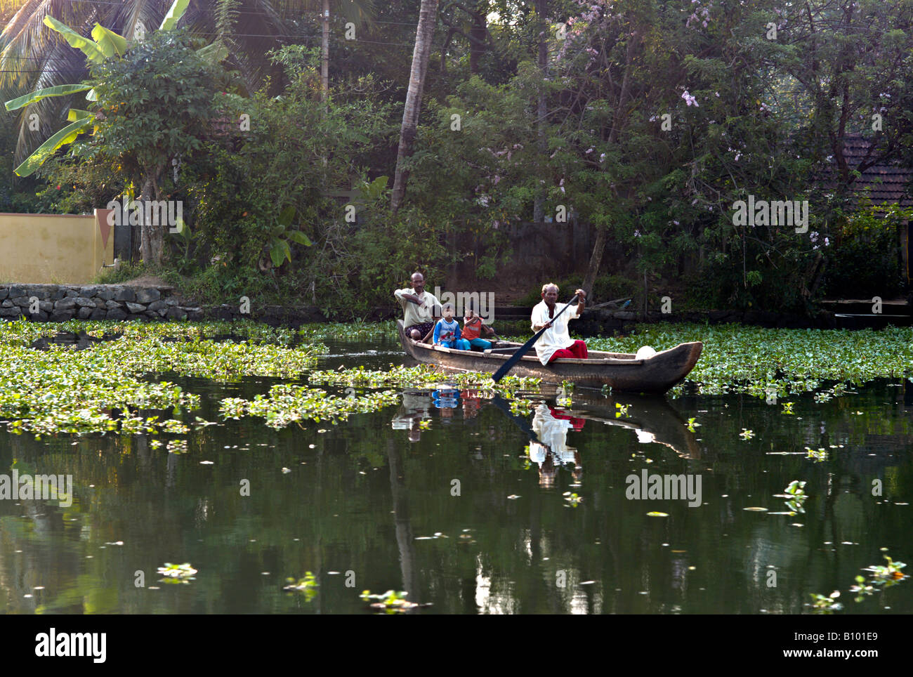 INDIA KERALA Two Indian men and three boys rowing their wooden canoe ...