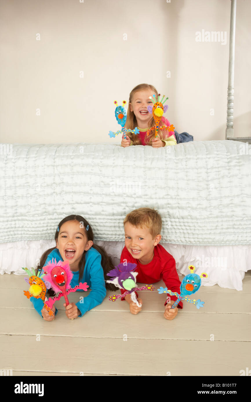 three children play on a bed with home made wooden spoon puppets Stock ...