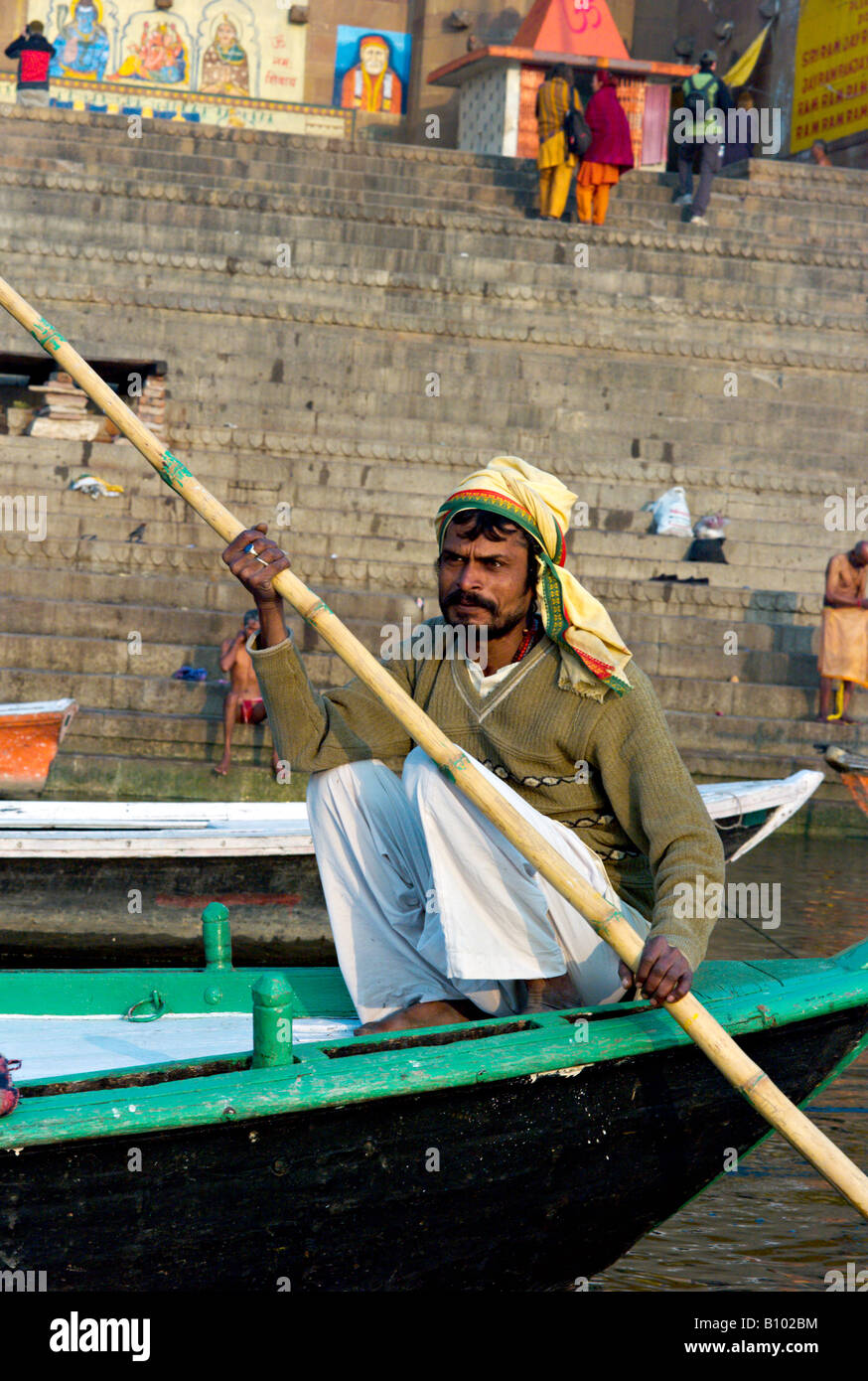 INDIA VARANASI Indian boatman rowing his boat on the Ganges River at ...