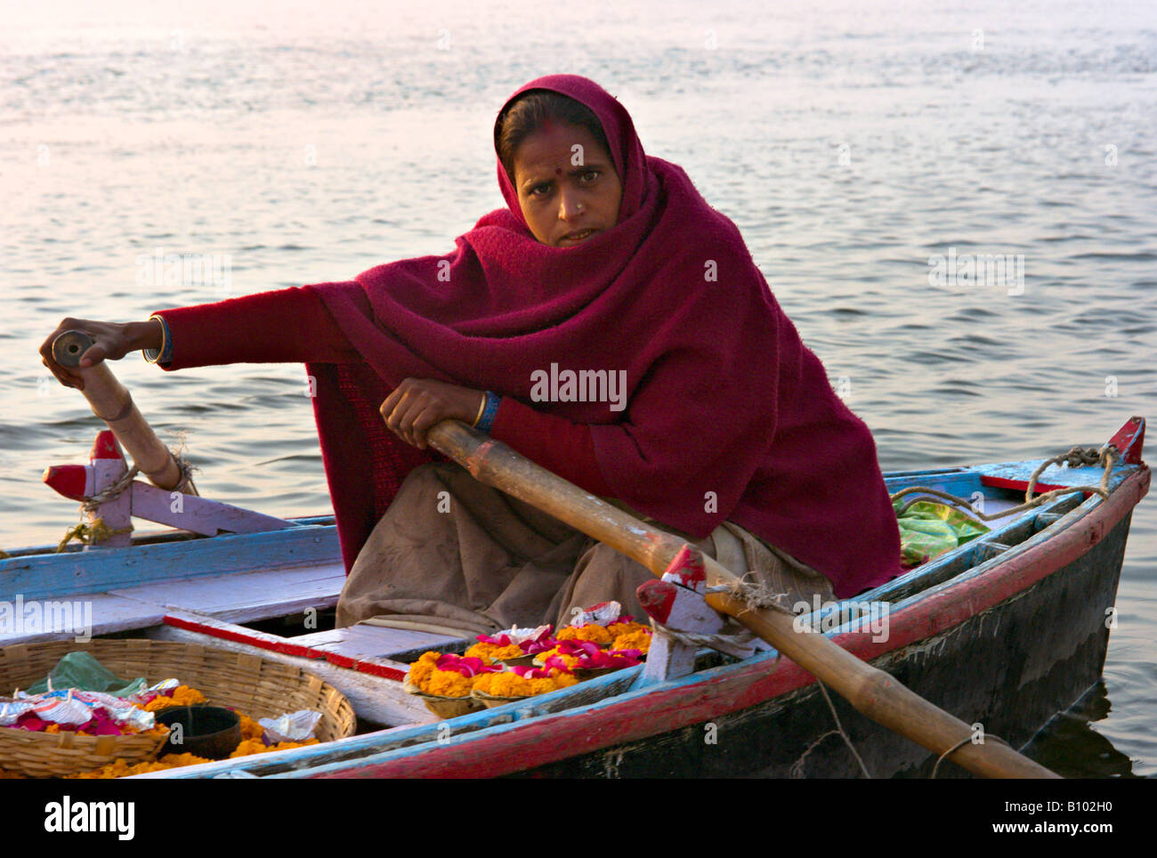 INDIA VARANASI Indian woman rowing a boat on the Ganges River at ...