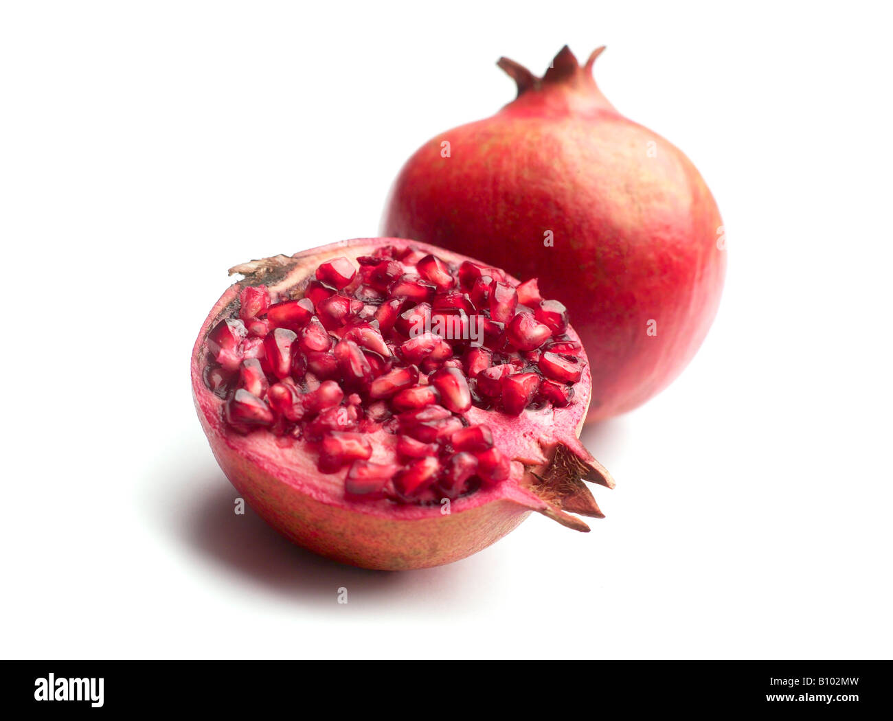 POMEGRANATE ON A WHITE BACKGROUND ONE WHOLE,ONE CUT OPEN TO SHOW THE ...