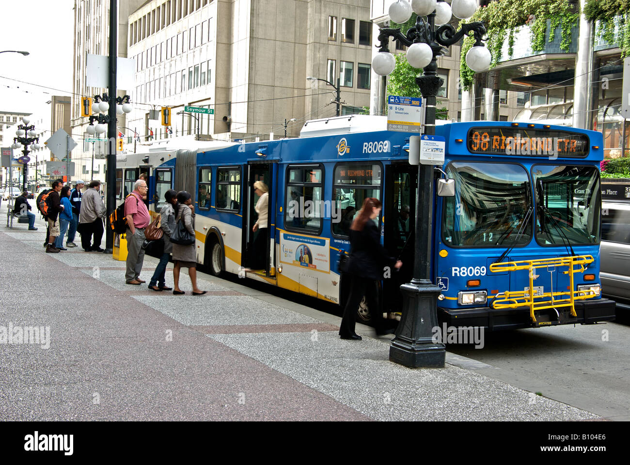 Morning commuters boarding an articulated public transit diesel bus ...