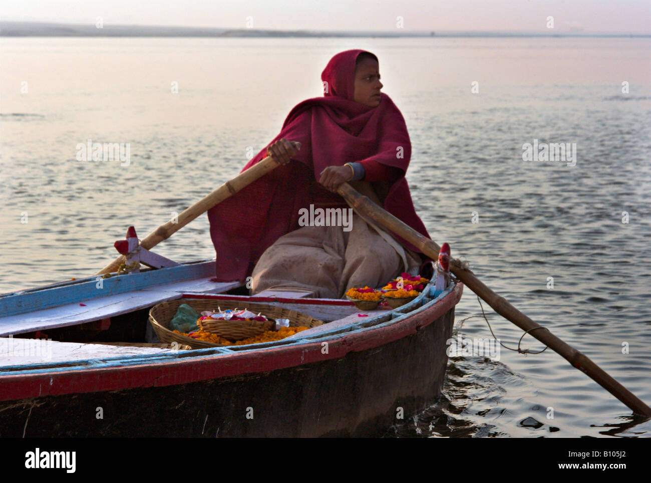 INDIA VARANASI Indian woman rowing a boat on the Ganges River at ...