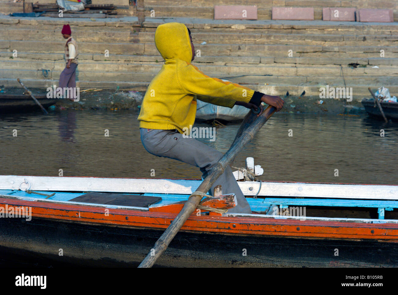 INDIA VARANASI Very young Indian boy uses all of his strength to row a ...