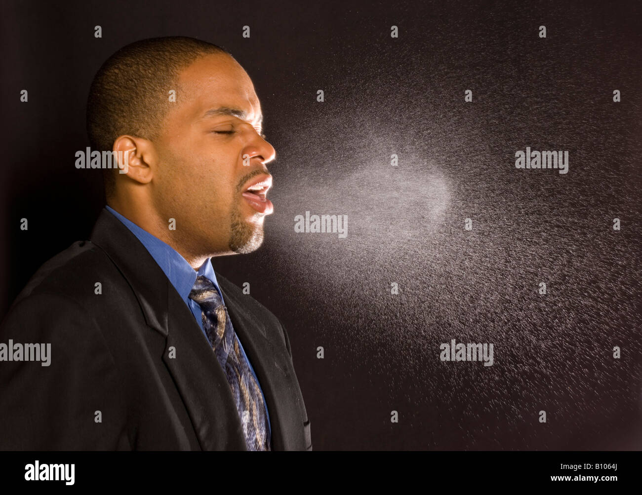 Man sneezing. Germs are visible by using special lighting techniques ...