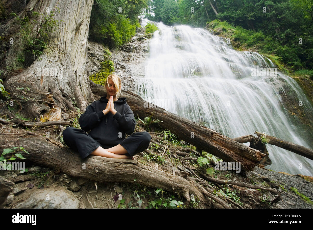 Woman meditating by waterfall Stock Photo - Alamy