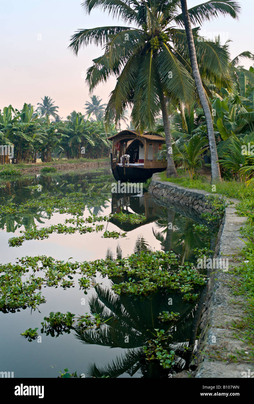 INDIA KERALA Renovated rice boat at sunset on canal in the backwaters ...