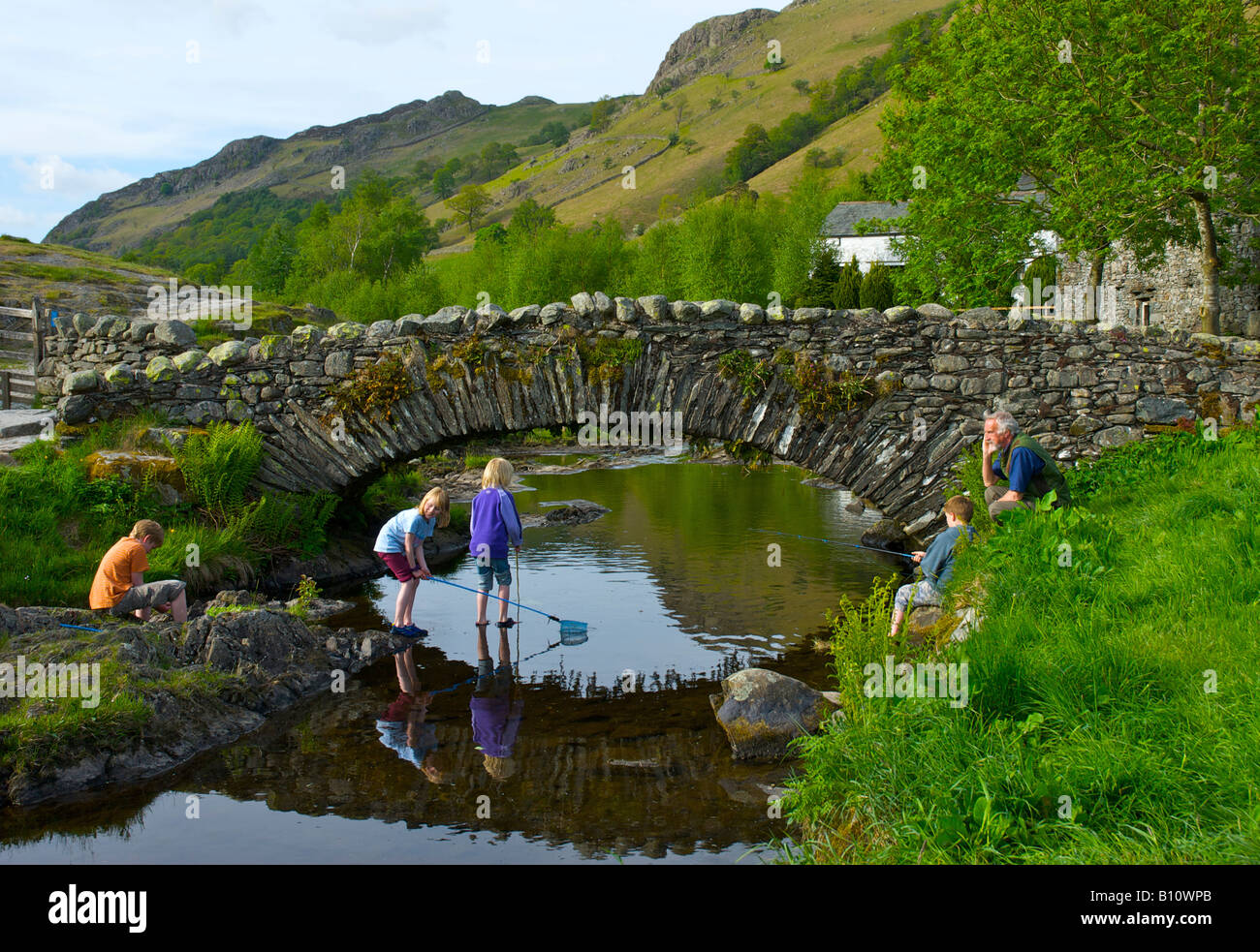 Children fishing next to the old packhorse bridge at Watendlath ...
