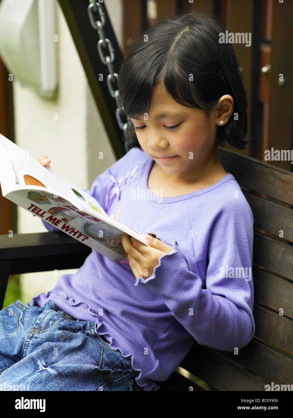 A girl reading a book on swing Stock Photo - Alamy