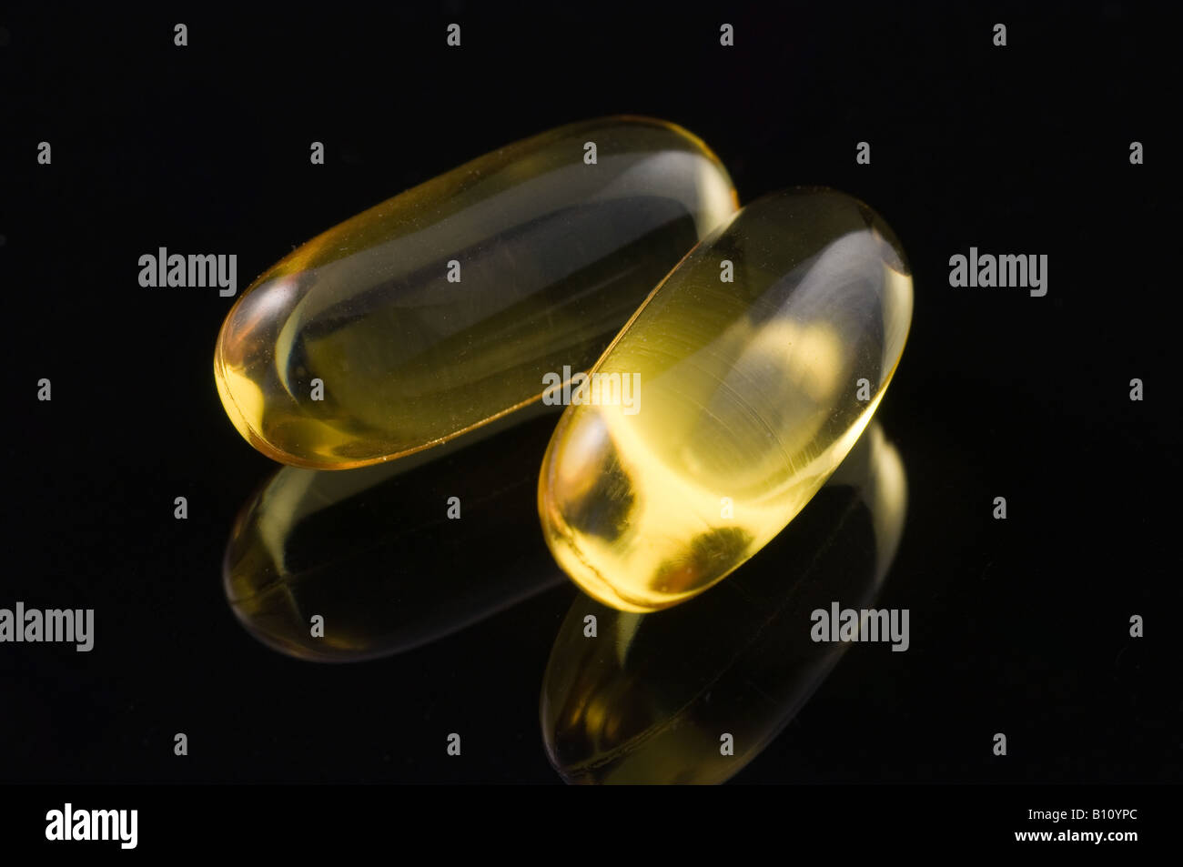 Closeup of two fish oil tablets on a shiny black background Stock Photo ...